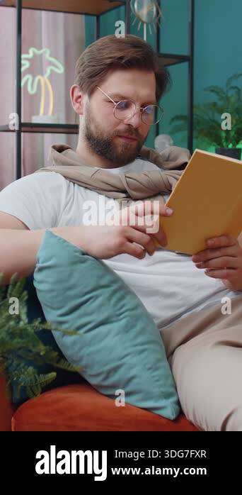 Young man relaxing interesting book, turning pages smiling enjoying ...