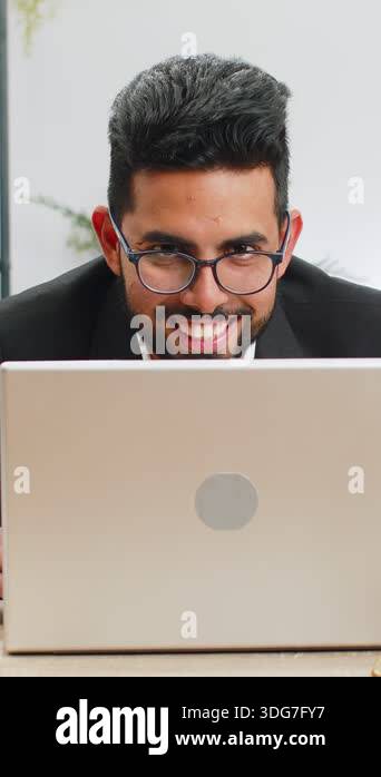 Indian businessman hiding behind laptop computer, making funny face ...
