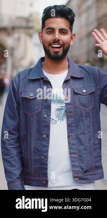 Hello. Young Indian man smiling friendly at camera, waving hands ...