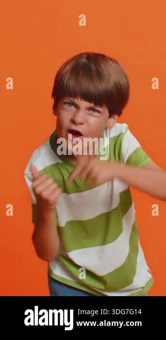 Aggressive angry young preteen child boy kid trying to fight at camera ...