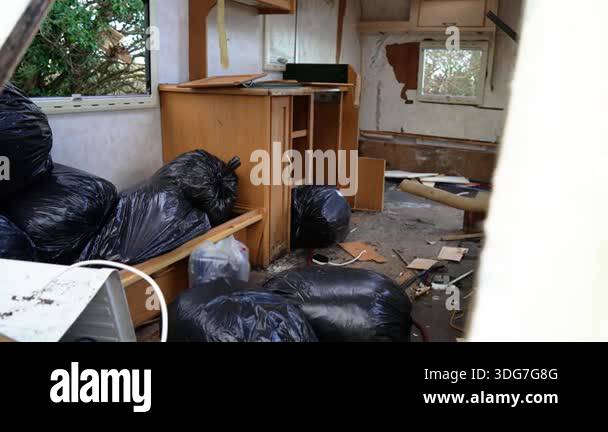 Interior scene revealing abandoned caravan cluttered with trash bags ...