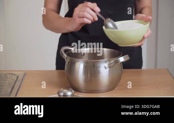 Scooping rice from bowl into pot. Unrecognizable person adding grains ...