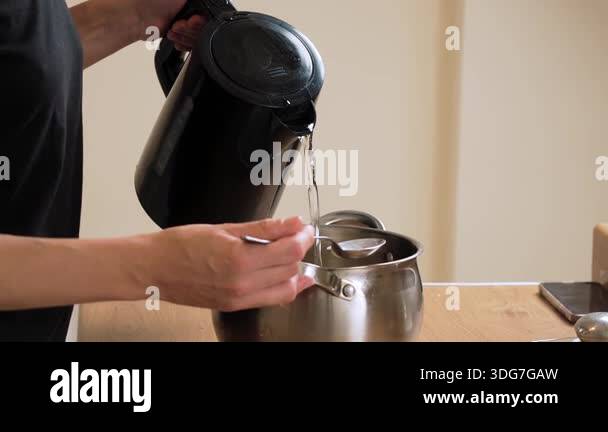 Pouring boiling water from kettle into pot. Unrecognizable person ...
