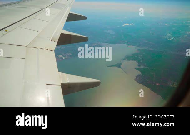 Plane flying above coastal land with towns and rivers meeting sea, view ...