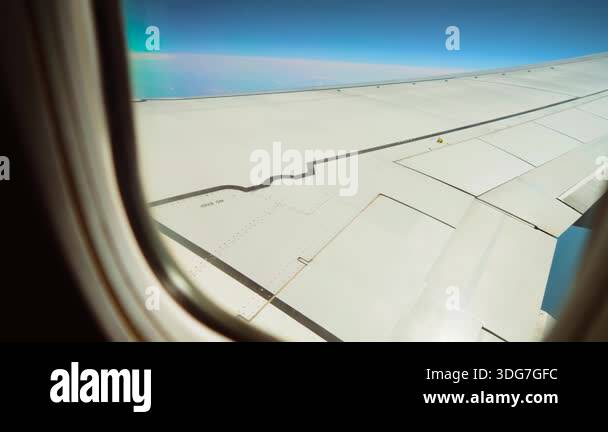 Aeroplane flying above bright sky and blue ocean, view from window ...