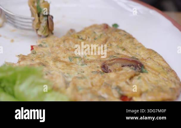 An omelet is shown on a plate with a fork and knife nearby for eating ...