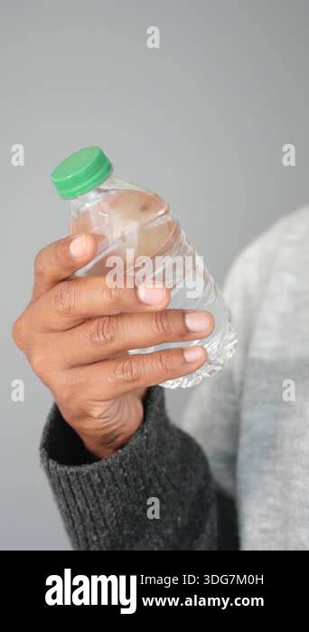 A hand is holding a clear water bottle with a green cap Stock Video ...