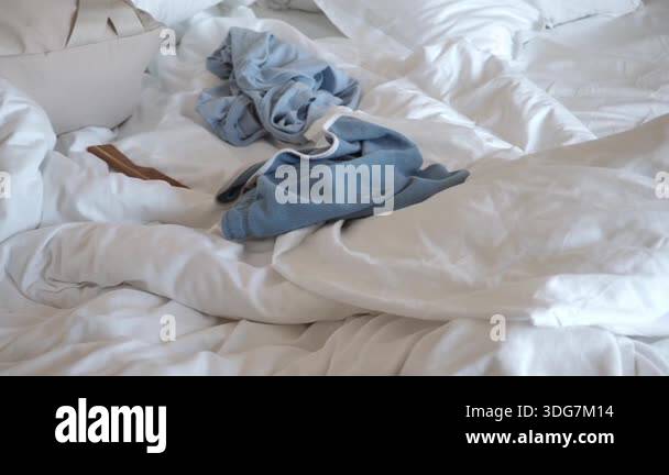 Clothes are laid out on a messy bed with bright light coming in Stock ...