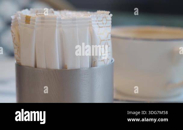 Sugar packets are placed near a cup of coffee on the table Stock Video ...