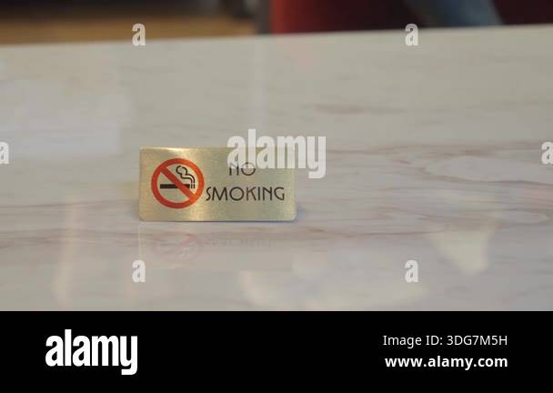 A sign stating no smoking sits on a table in a public area Stock Video ...