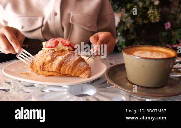 A person sits at a table with a croissant and coffee. They are ready to ...
