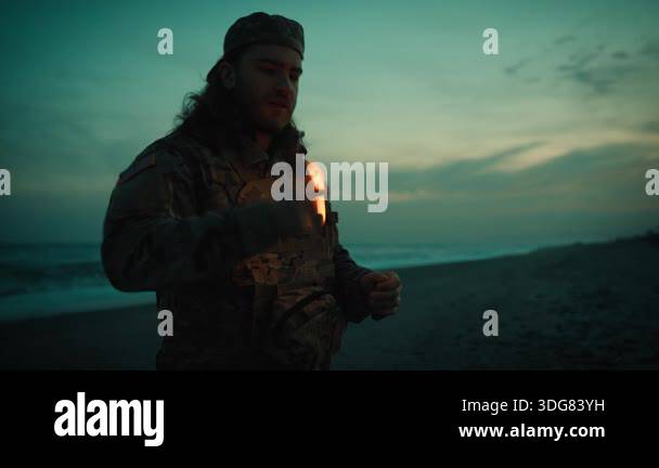 Lighting a chemical light by an American soldier at night on a beach ...