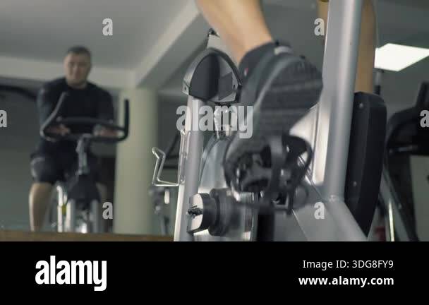 A young man in sportswear engages in a cardio warm-up on a stationary ...
