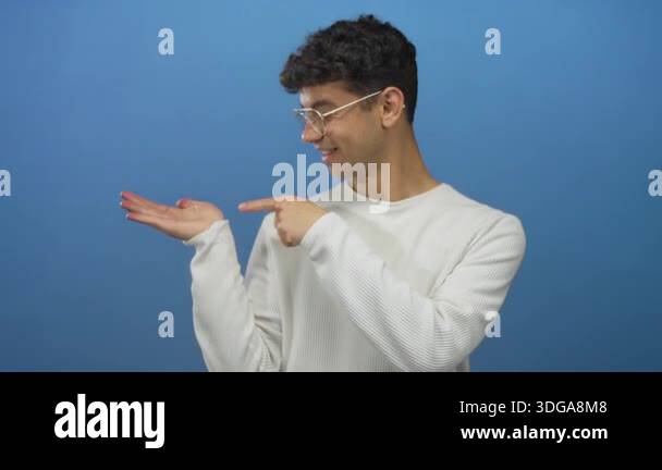 Young hispanic man pointing finger to open palm in studio setting with ...