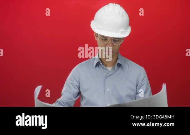 Young hispanic engineer holds large blueprint in studio setting wearing ...