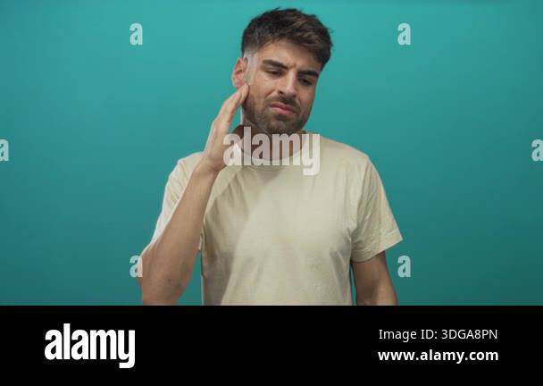 Young hispanic man wearing beige t shirt cups cheek for toothache in ...
