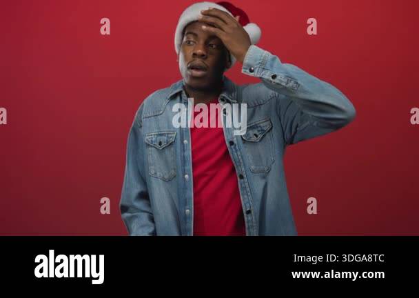 Man wearing santa hat, denim jacket and red shirt holds hand on ...