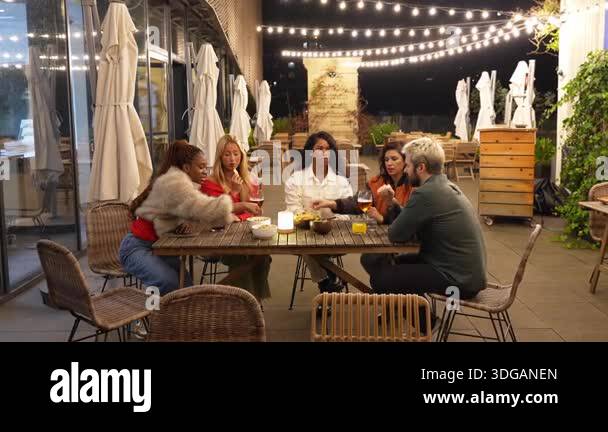 Four friends gather at a rooftop bar, enjoying drinks, conversation ...