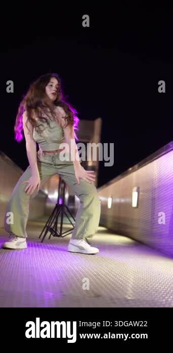 Energetic female dancer performing hip hop moves on a metallic bridge ...