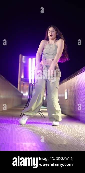 Energetic female dancer performing various moves on a metallic bridge ...