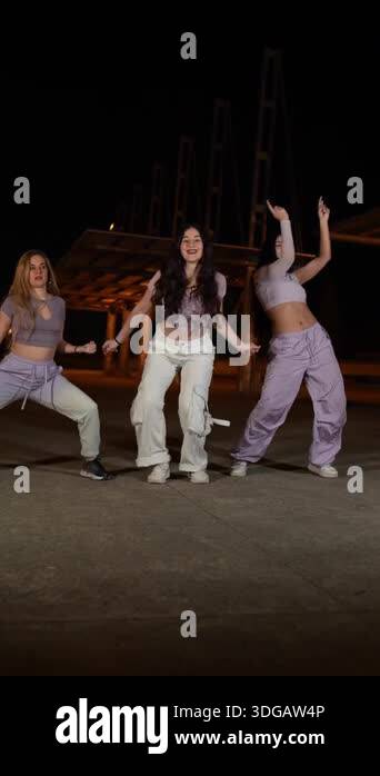 Professional dance crew performing energetic street dance choreography at urban nighttime ...