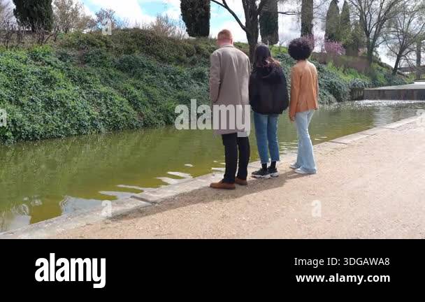 Group of friends posing for photos by canal in a park, turning from ...