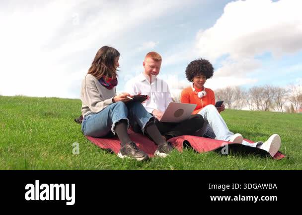 Students working together on a project outdoors, utilizing a laptop and ...