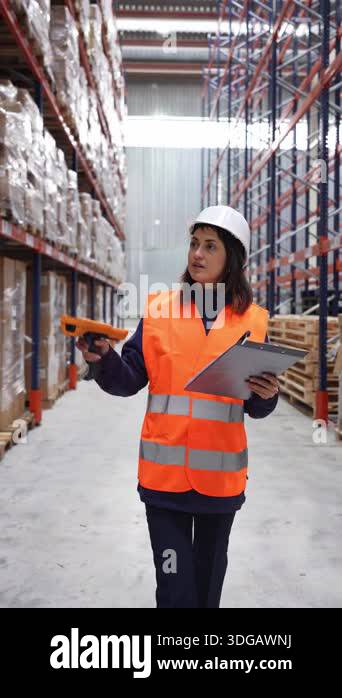 Warehouse worker wearing safety vest and helmet scanning barcodes and ...