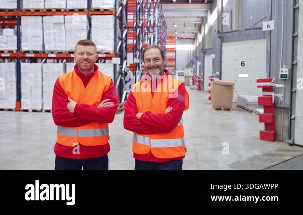 Warehouse professionals wearing orange safety vests and red shirts ...