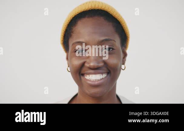 Portrait of smiling black woman wearing yellow cap against white ...