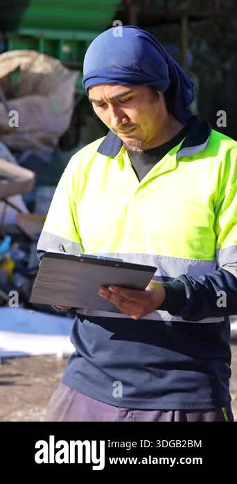 Worker in a recycling facility assesses pallet recycling operations ...