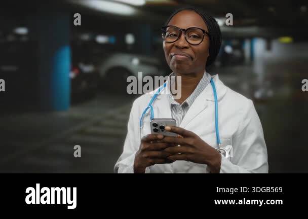 Smiling woman doctor with stethoscope texting on smartphone in indoor ...