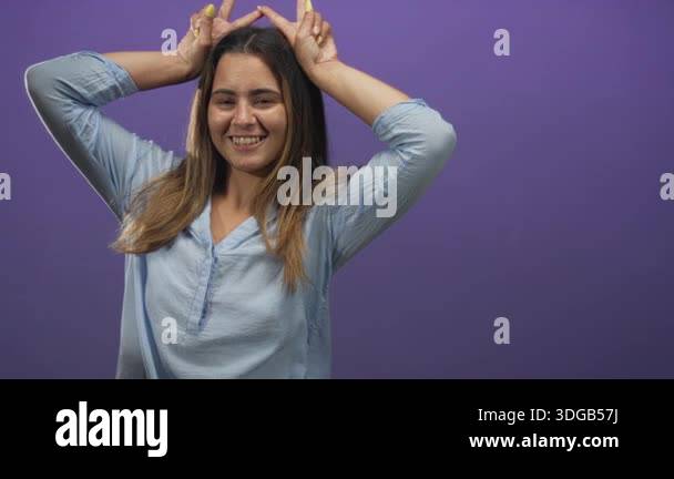 Woman with hands making bunny ears gesture, eyes closed and smiling ...