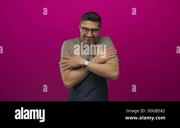 Man wearing denim apron and glasses with crossed arms hugging chest in ...