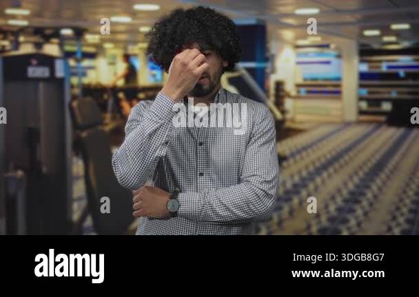 Man pinches nose with hand and folds arm near cardio machines and ...