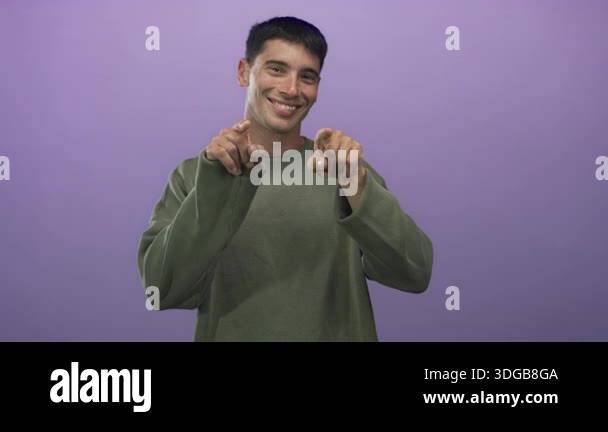 Young hispanic man in green sweater beckons with hands and smiles in ...