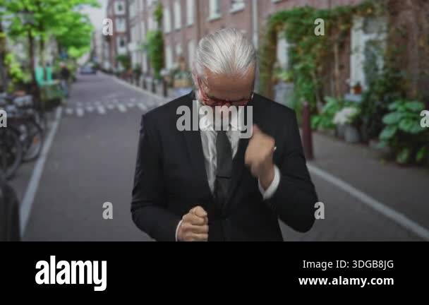 Man in suit and tie clenching fists near chest and smiling while ...