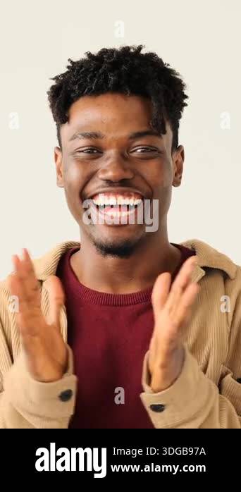 Vertical video of a joyful young black man clapping hands and smiling ...