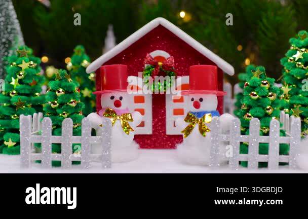 A red house surrounded by snowmen and Christmas trees behind a fence ...