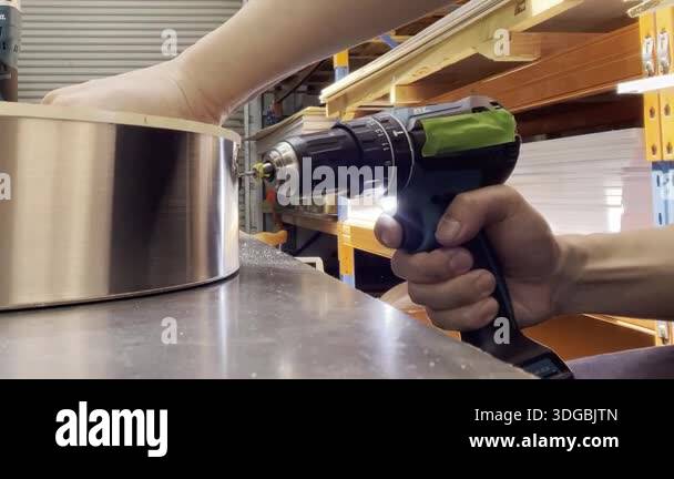 Hands assembling stainless steel lightbox frame using cordless drill ...