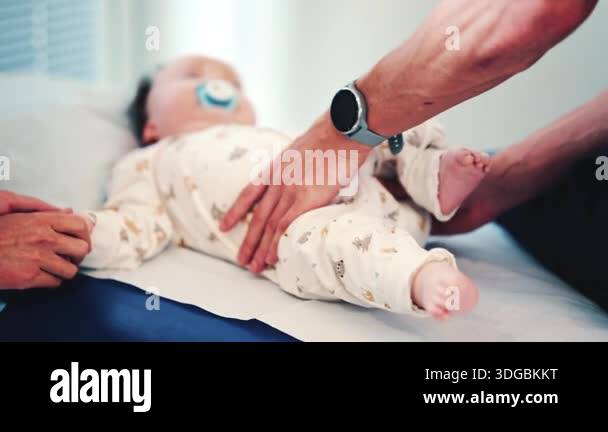 Calm baby wearing a pacifier lying on a medical or therapy table during ...