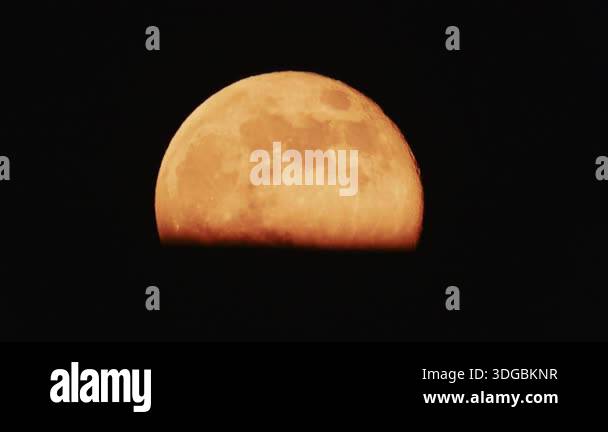 Large full moon rising against a dark night sky with clear details and ...