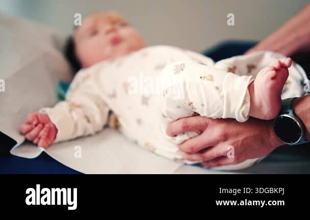 Infant lying on a padded examination table while caregivers gently ...