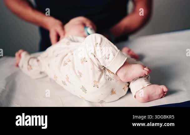 Baby lying on its back on a medical table while caregivers prepare for ...