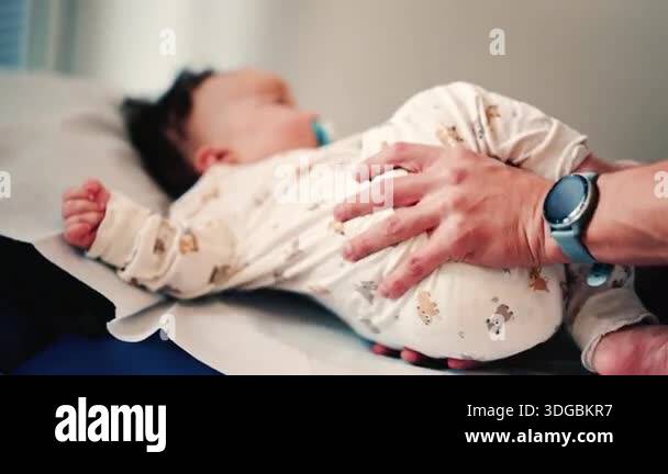 Infant lying on a padded examination table while caregivers gently ...