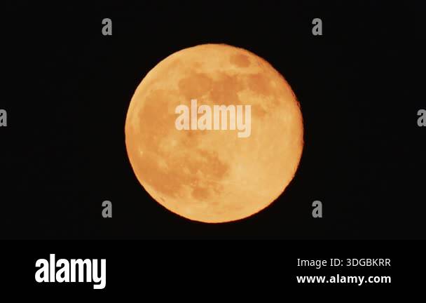 Large full moon rising against a dark night sky with clear details and ...