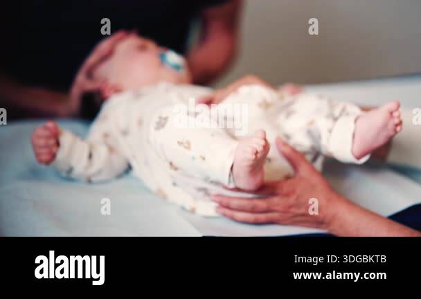 Infant lying on a padded examination table while caregivers gently ...