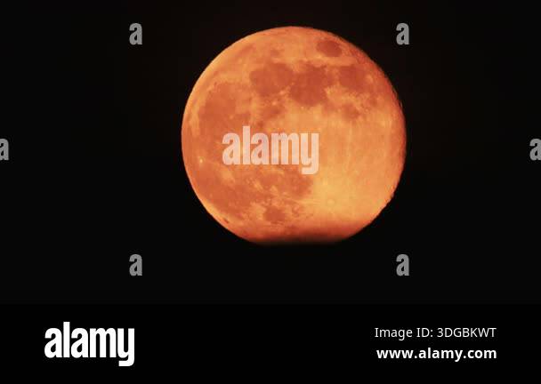 Large full moon rising against a dark night sky with clear details and ...
