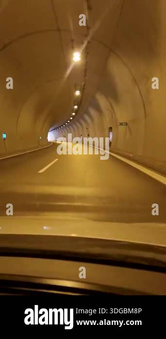 POV driving shot through an illuminated modern highway tunnel in Greece ...