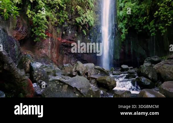 tall mossy waterfall dropping over basalt cliff, tumbling stream across ...